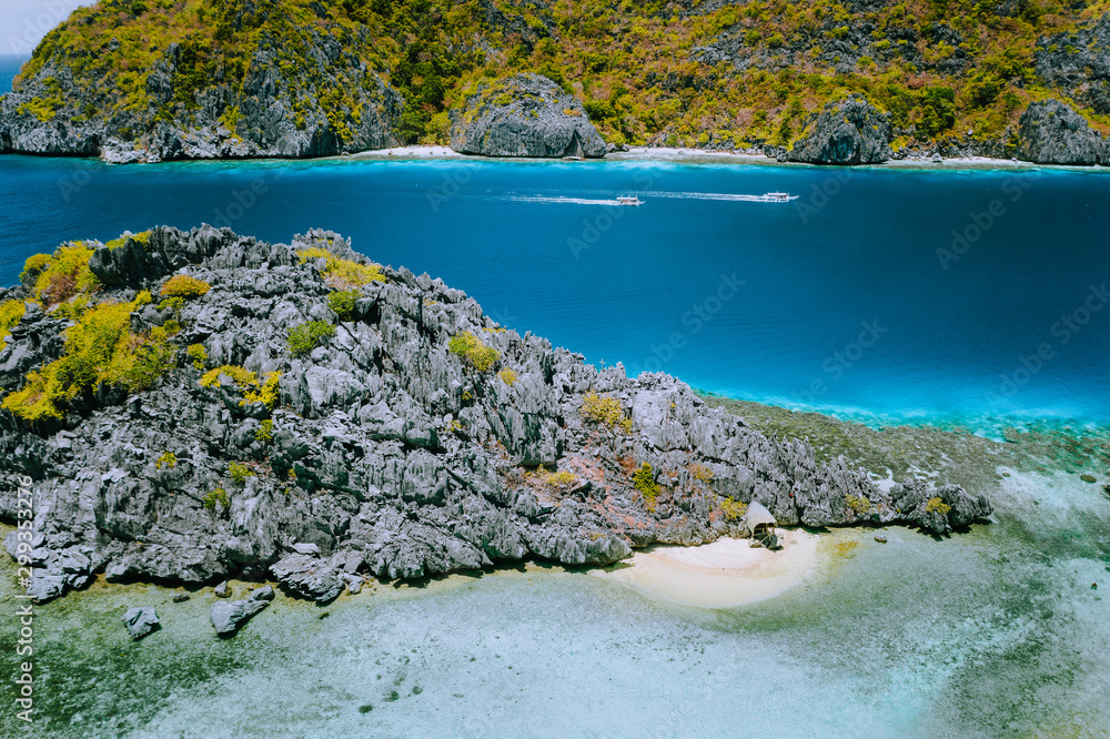Limestone karst star beach at Matinloc Island with tourist boats in ...