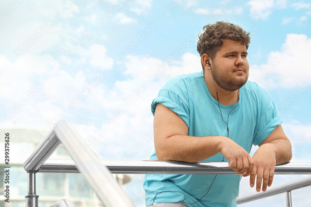 Young overweight man leaning on railing outdoors Stock Photo | Adobe Stock