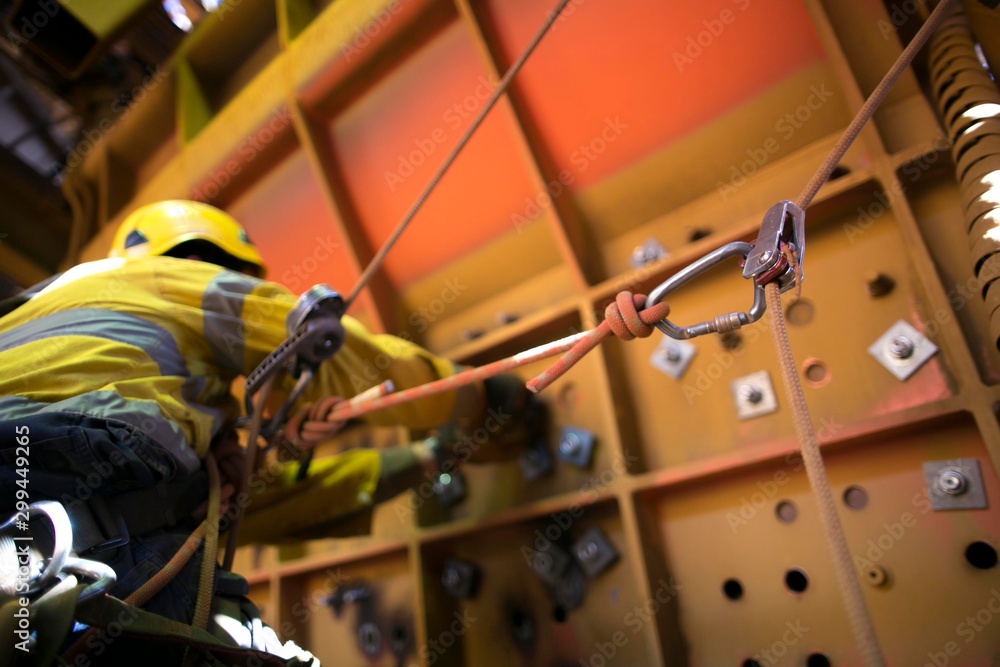 Rope access miner working at height hanging on harness commencing chute ...