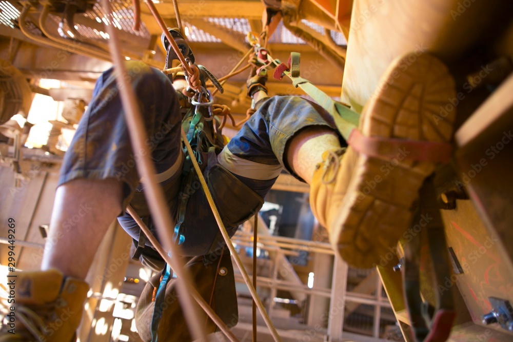 Defocused picture of rope access miner working at heights hangin on two ...