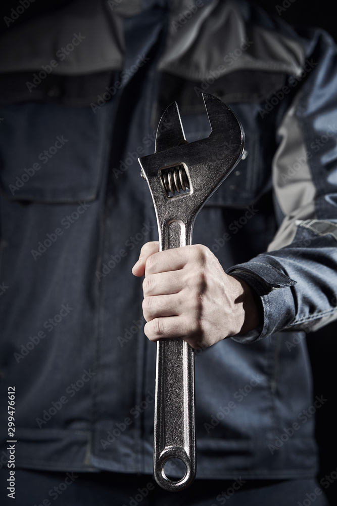Professional construction worker shows a wrench on a dark background ...