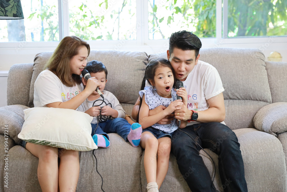 Happy Asian family, father, mother daughter and son singing karaoke on ...