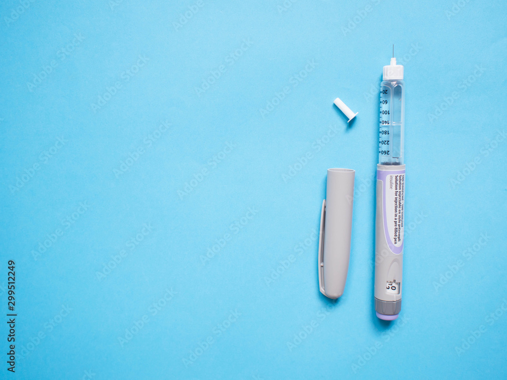 Insulin pen with cap on light blue background. Medical devices is used ...
