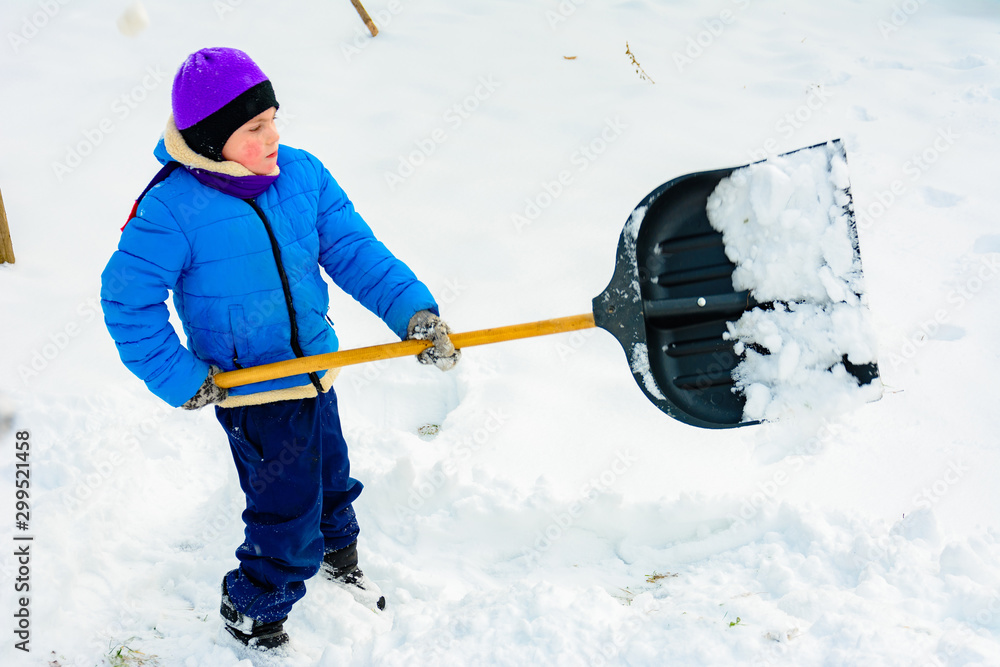 Smiling boy is carrying snow on a shovel, Child cleans the yard after a ...