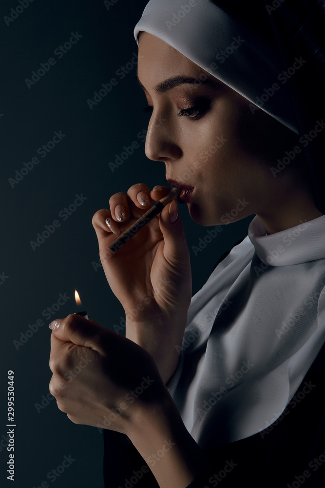 Close-up portrait of a nun, taking on a black background. She wearing ...