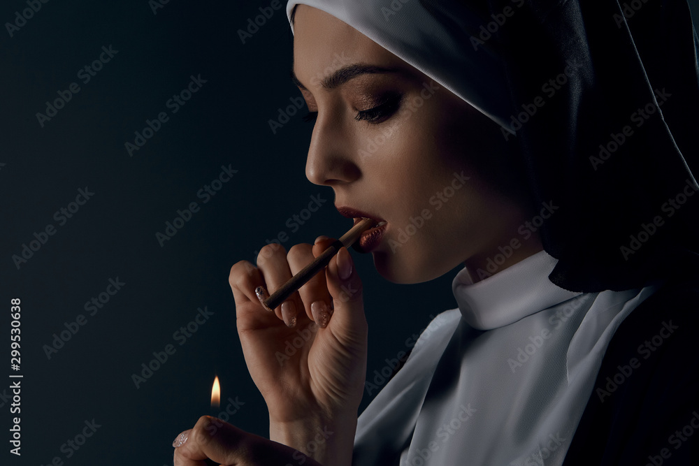 Close-up portrait of a nun, taking on a black background. She wearing ...