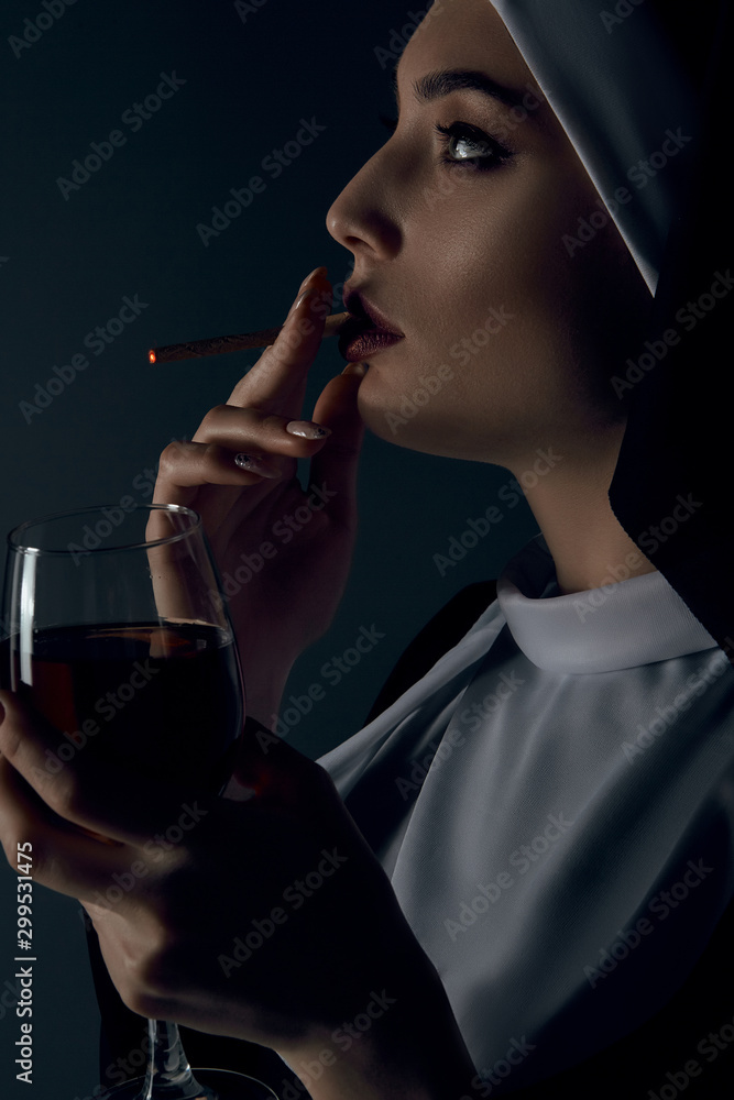 Close-up profile portrait of a nun, posing on a black background. She's ...