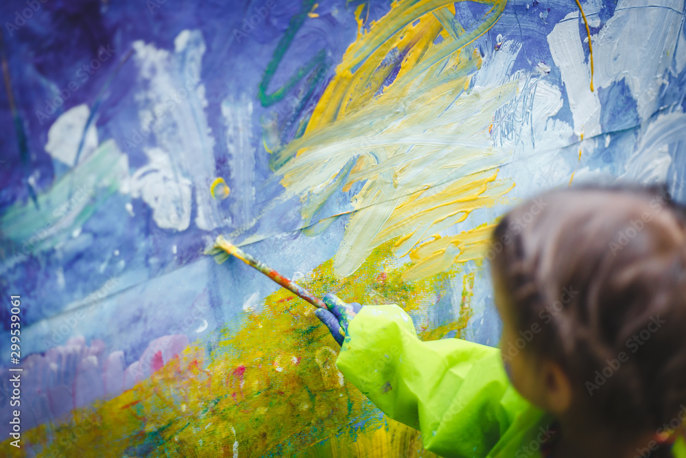 Smart little girl drawing on the wall. little girl child stained in ...