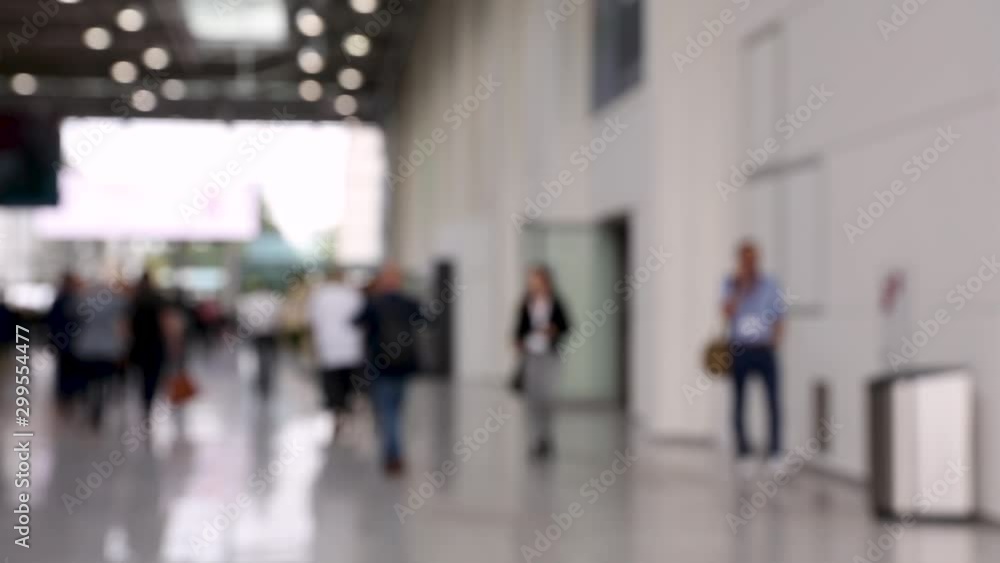 Blurred crowd of people passing by in hallway of convention center ...