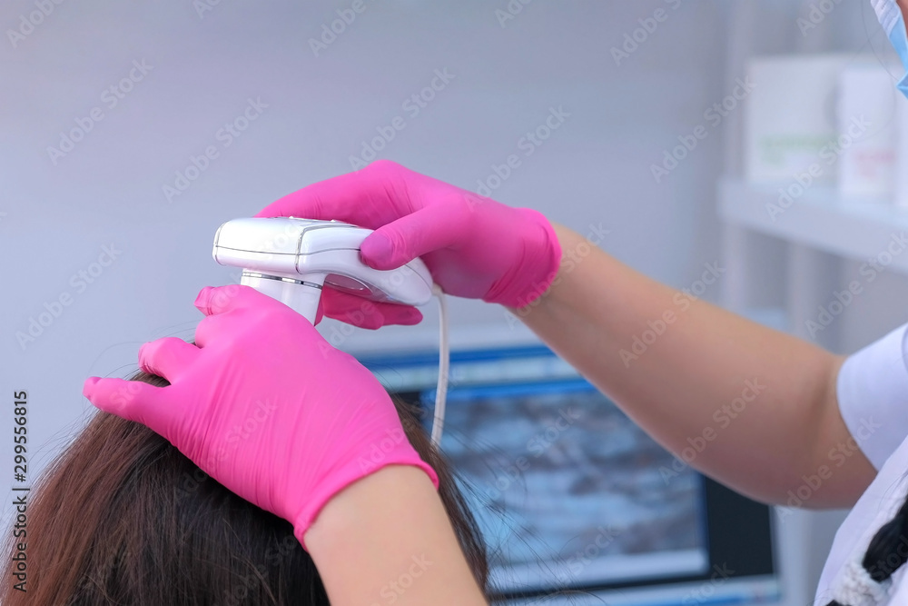 Trichologist examines woman patient's hairs using computer trichoscopy ...