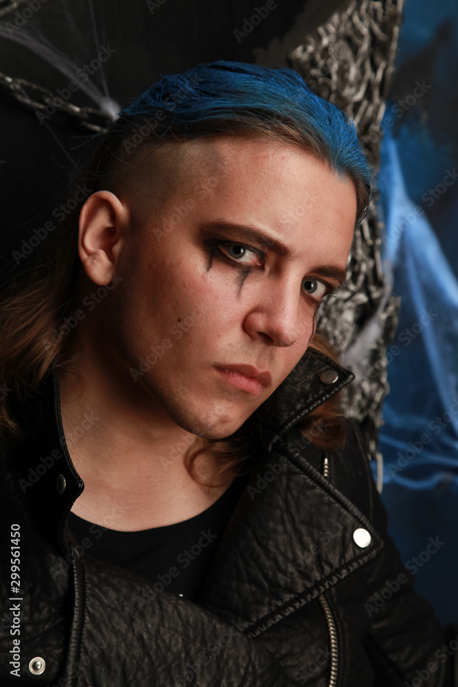 Teen alt boy with blue hair and shaved head dressed in black on dark ...