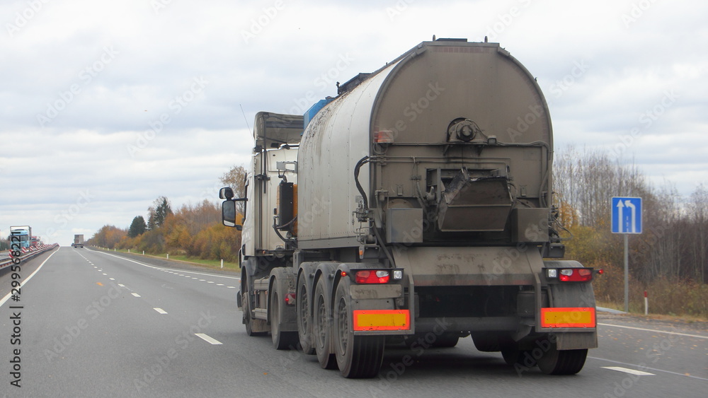 Bitumen truck with a round barrel semi trailer moving on a two-lane ...