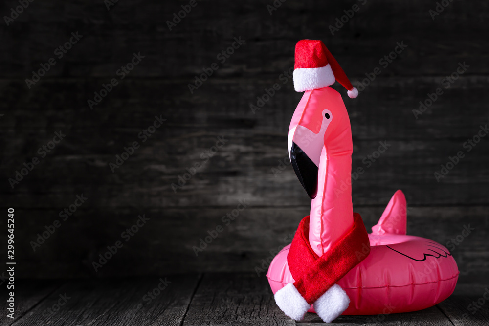 Inflatable pink flamingo in Santa Claus hat and red scarf on wooden ...