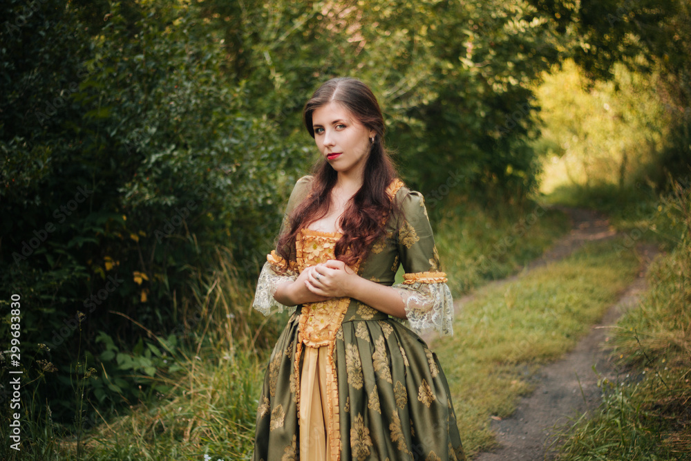 Beautiful young girl in a green rococo dress, walk through the park. A ...