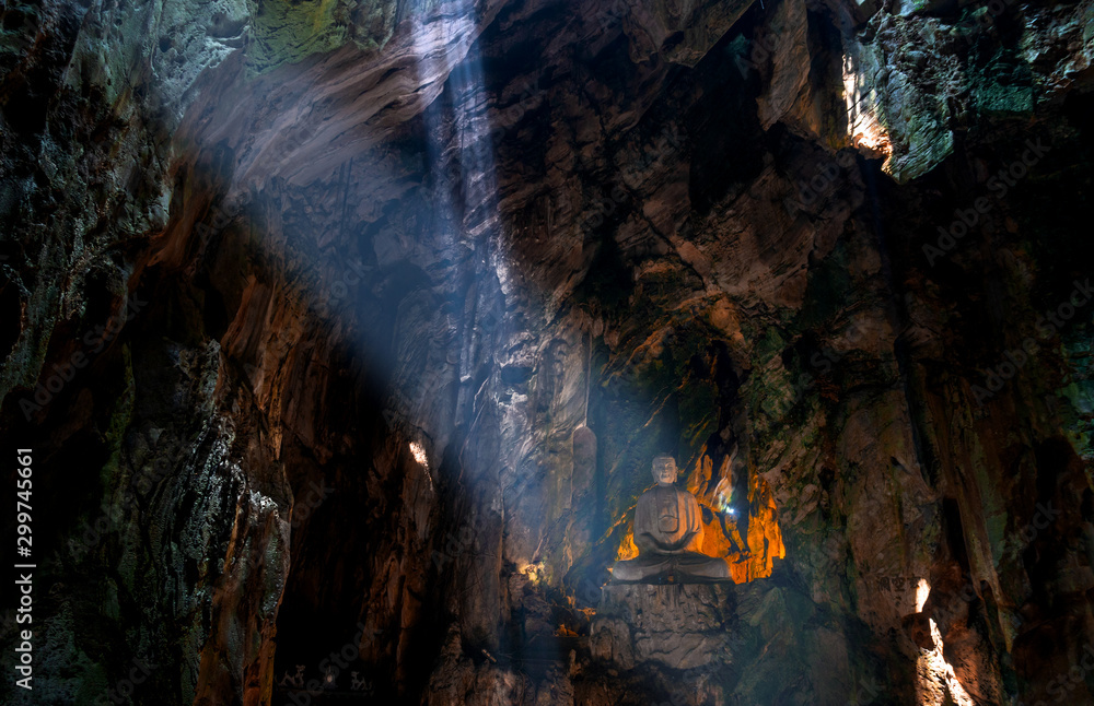 Buddha statue in a temple located in a cave in Vietnam. rays of light ...