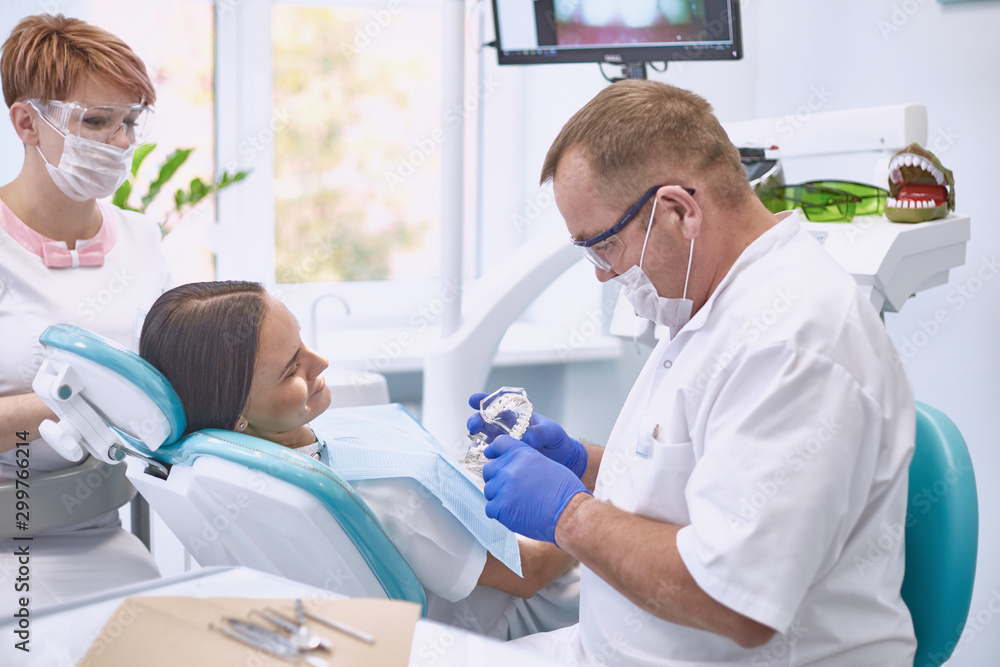 Doctor dentist treats teeth of a beautiful young girl patient. The girl ...