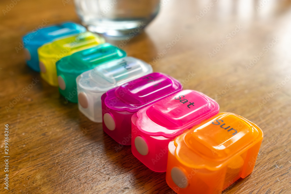 Shallow focus of a plastic pill dispenser seen on stable next to a ...