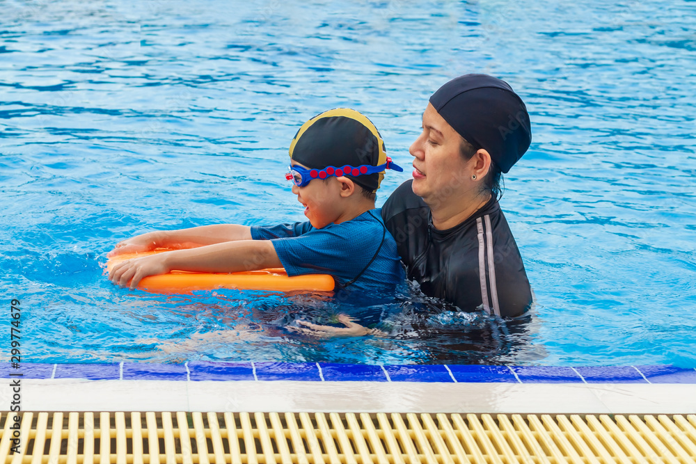 Little boy age 5 years old using the kicking board for learning to swim ...
