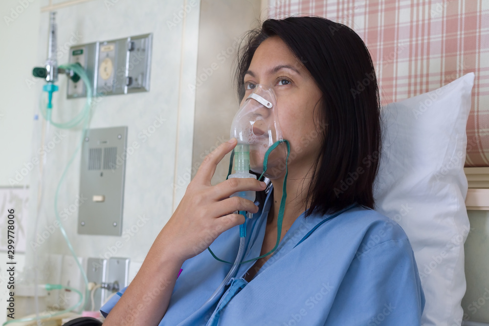 Sick beautiful female in blue cloth hold nasal mask with respiratory ...