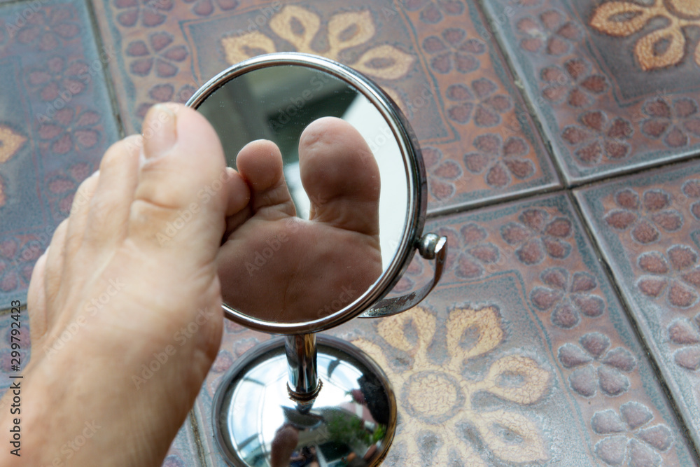 Person looking at the sole of the foot in a mirror. Stock Photo | Adobe ...