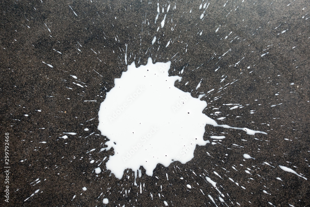 Top view of White milk spilled and splash on the dark floor surface ...