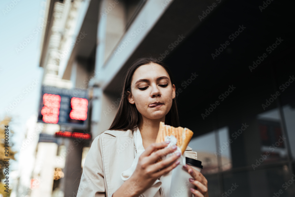 student is happy to eat a pie and drink coffee on a city street Stock ...