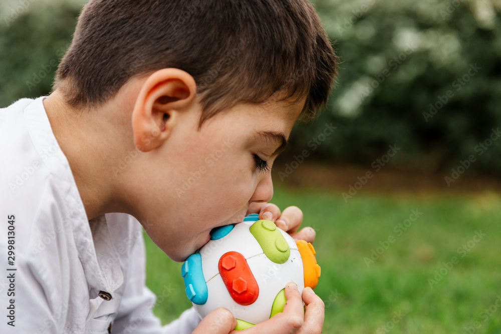 niño con discapacidad mordiendo jueguete. sensorial, morder, parque ...