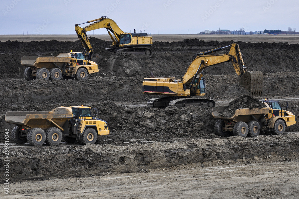 Excavators loading rock trucks with earthen fill material to be used ...