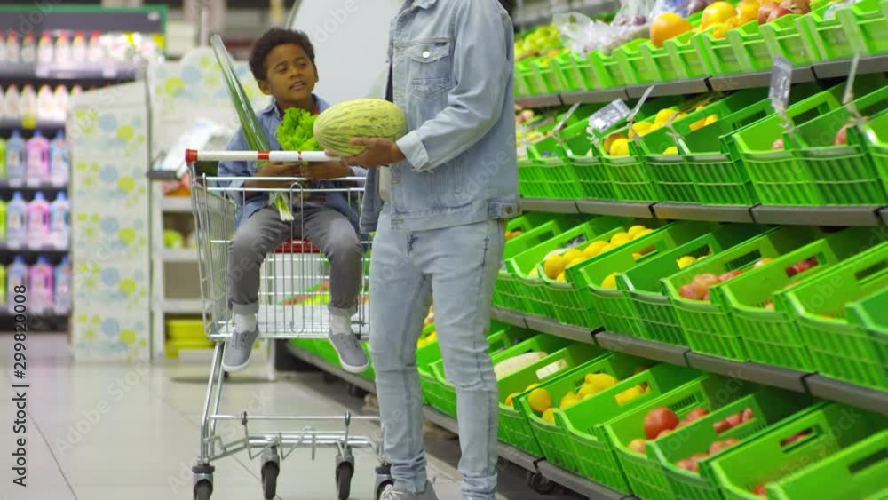 Tilt up shot of bearded black man in glasses holding melon, pulling ...