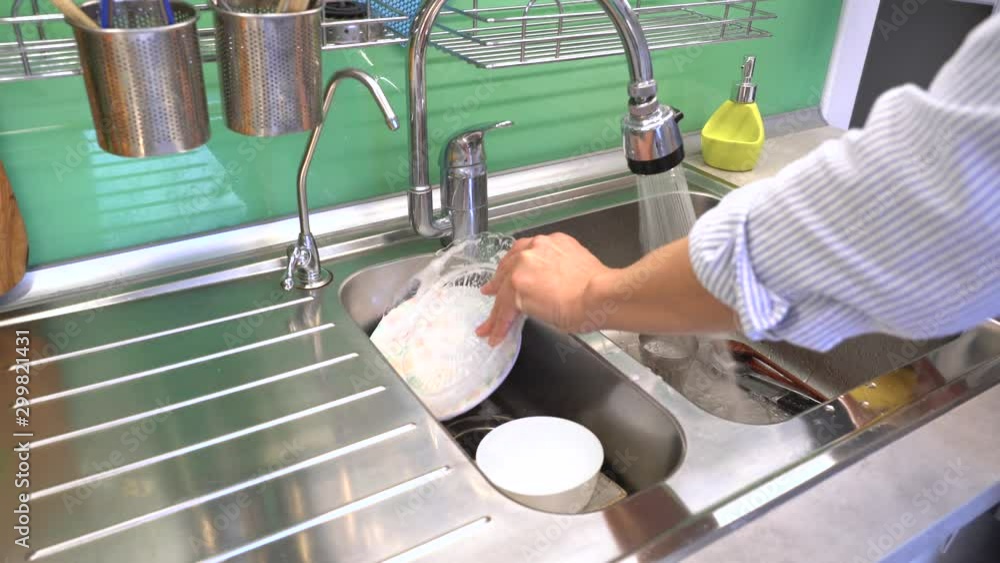 Lathering dirty dishes with dishwashing liquid and washing sponge ...