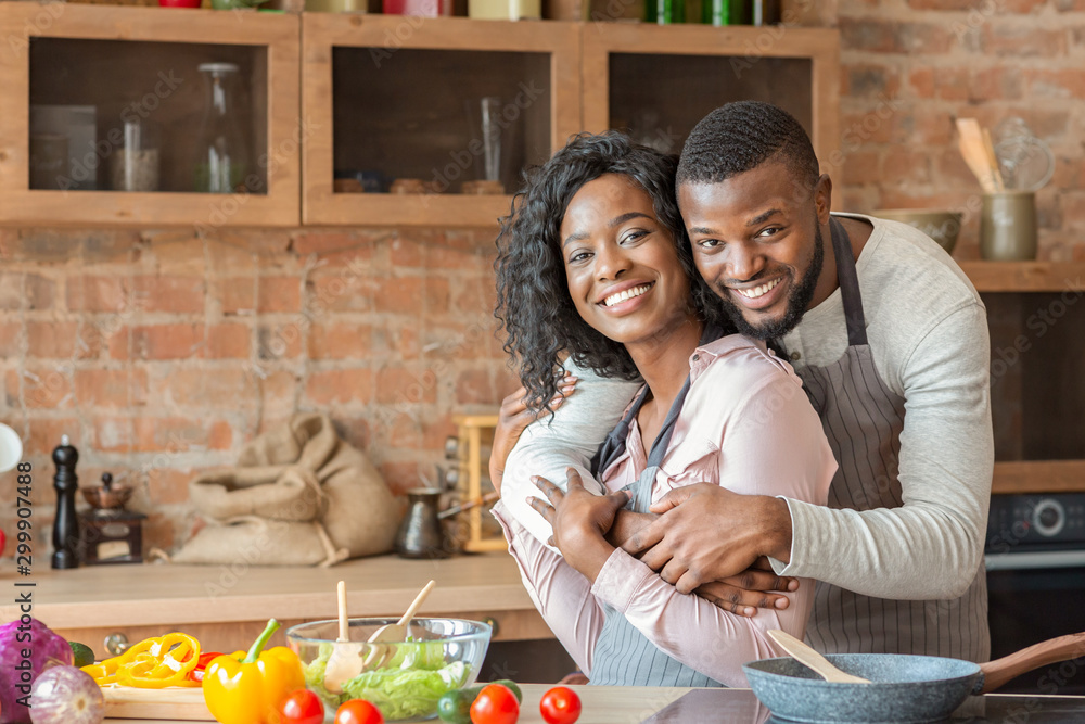 Handsome african man hugging his wife while cooking at kitchen Stock ...
