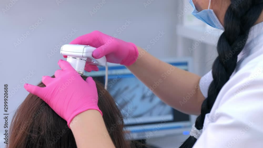 Vidéo Stock Doctor trichologist examines woman patient's hairs using ...