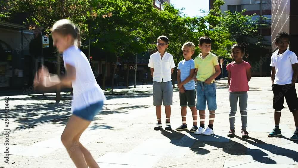 Smiling children playing rubber band jumping game and laughing outdoor ...