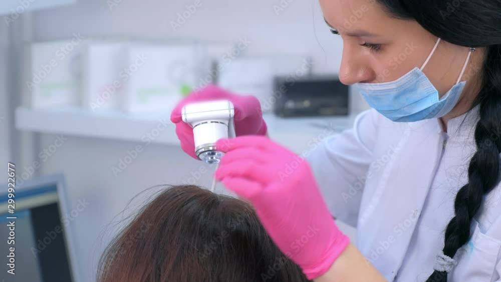 Trichologist examines woman patient's hairs using computer trichoscopy ...