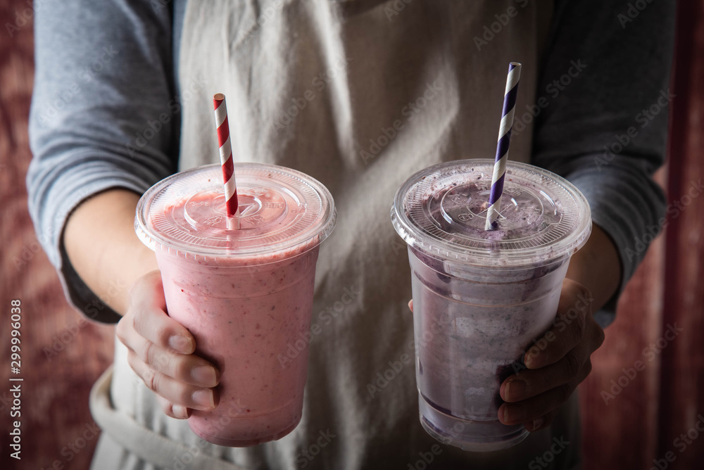 female with apron giving berry smoothie in plastic cup Stock Photo ...