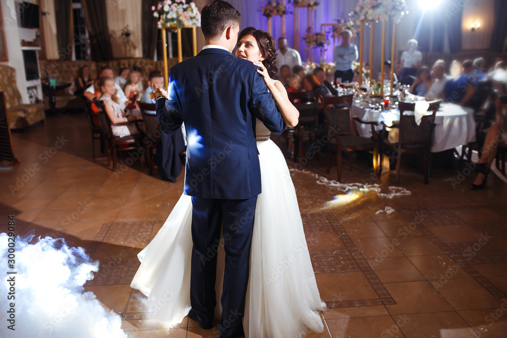 First wedding dance of newlywed. Groom holds bride's hand dancing with ...