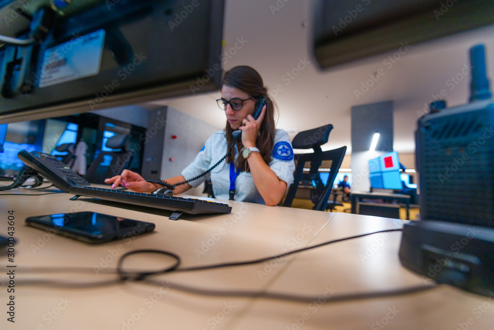 Female security guard operator talking on the phone while watching the ...