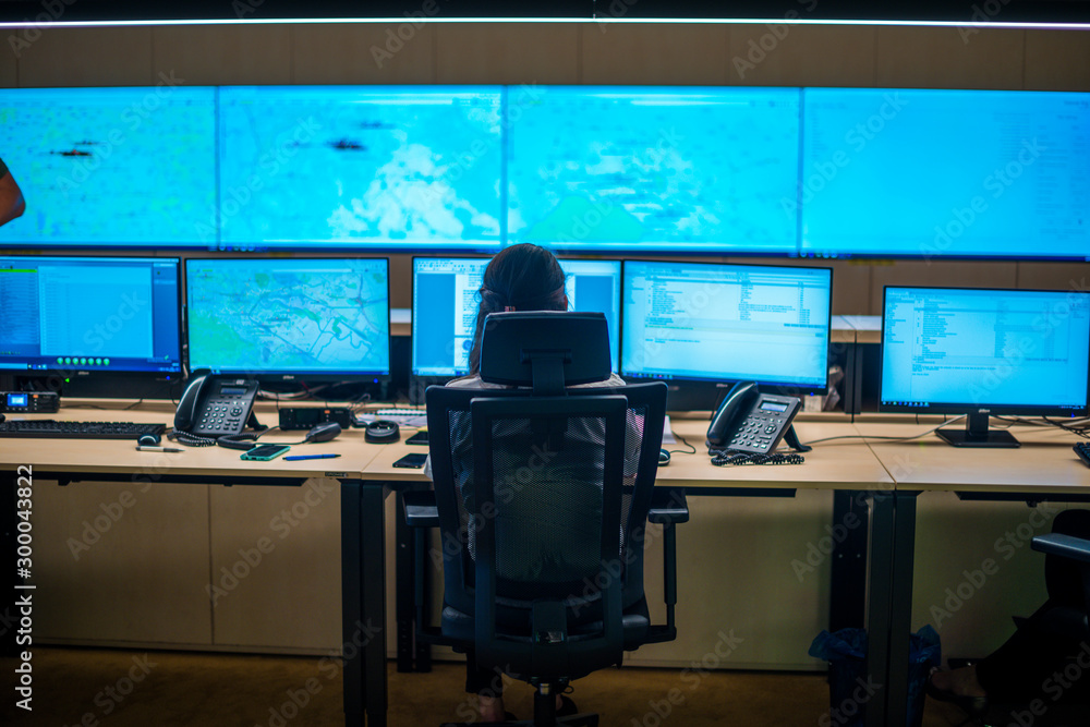 Female security guard sitting back and monitoring modern CCTV cameras ...