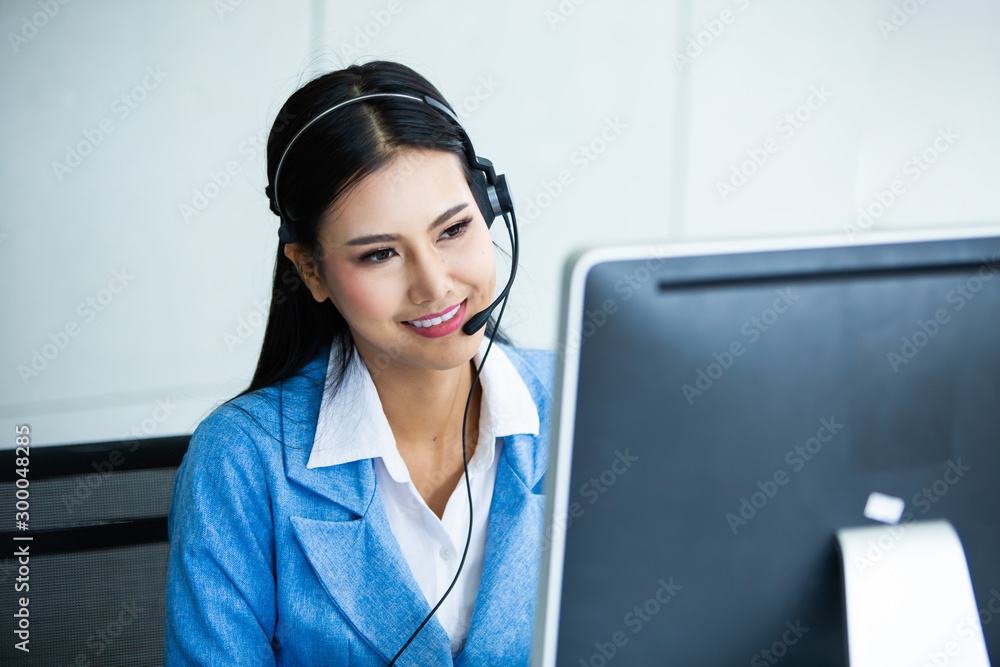 Attractive business woman Asian in suits and headsets are smiling while ...