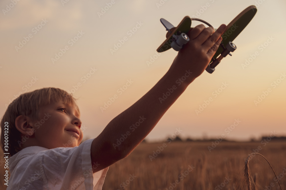 Happy child playing with a toy plane in nature during summer sunset ...