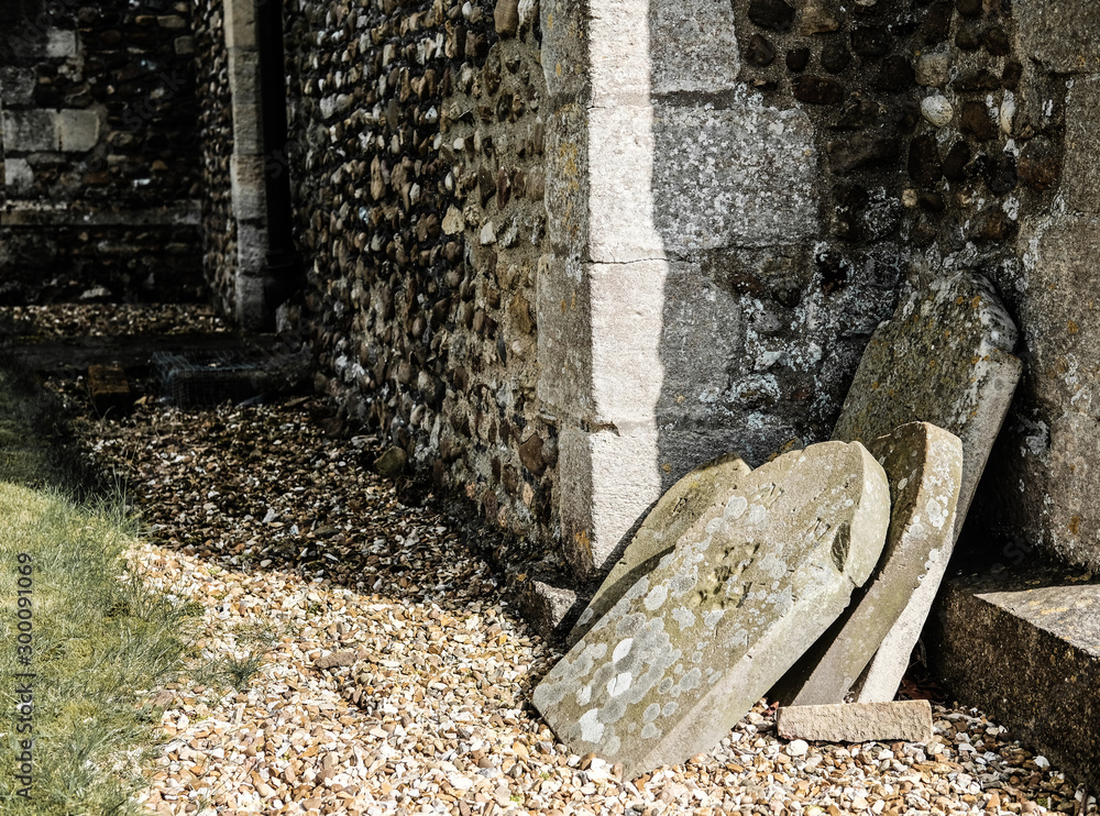 Briken grave stone seen stacked by an old, flint built English church ...