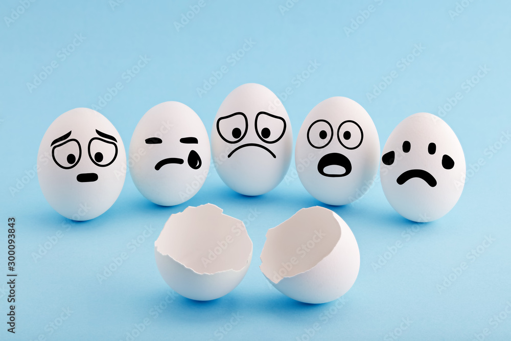 White chicken eggs with faces gathered around a broken egg shell and ...