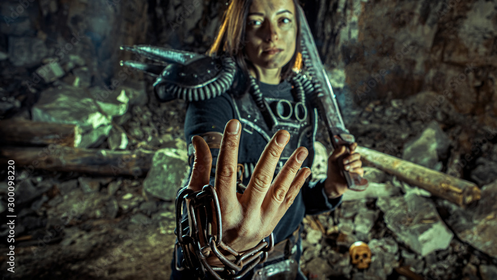 Post-apocalyptic woman with the chain and sword in hands on the dungeon ...