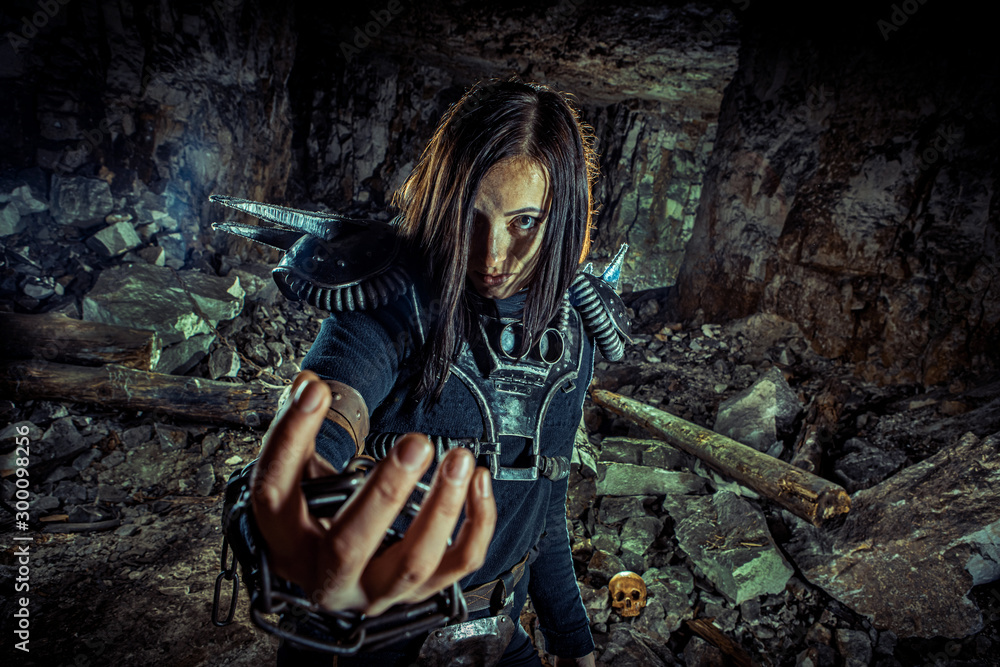 Post-apocalyptic woman with the chain and sword in hands on the dungeon ...