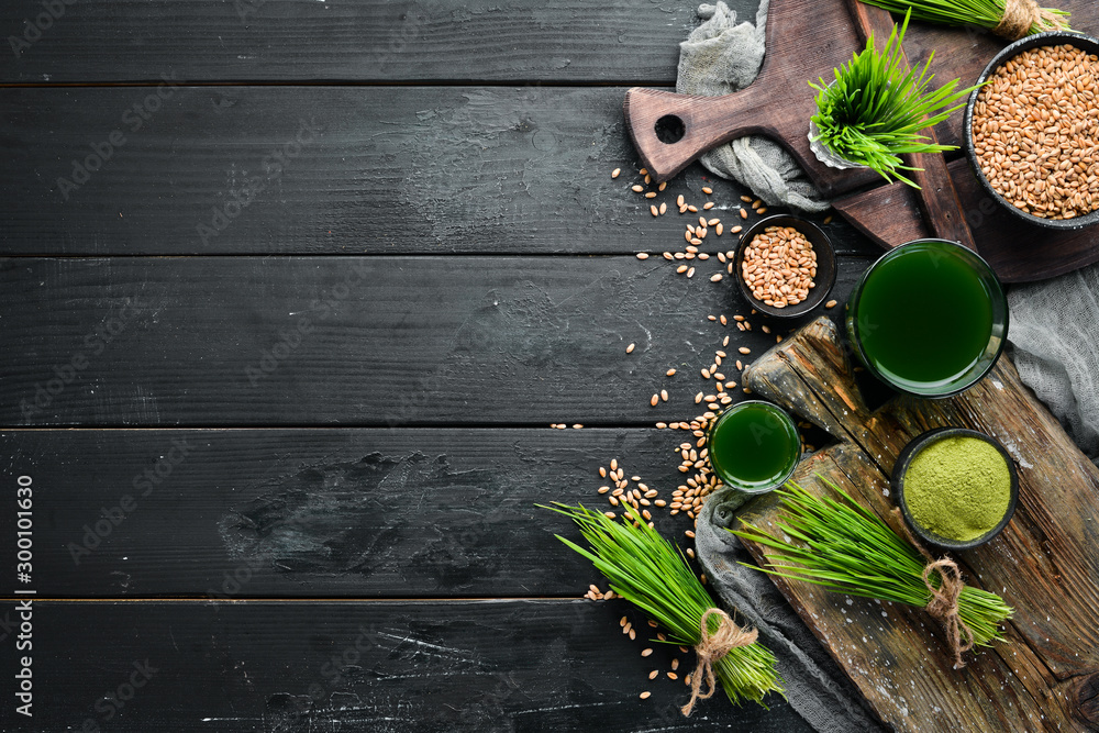 The juice from the green sprouted wheat, and wheat grains. On a black ...