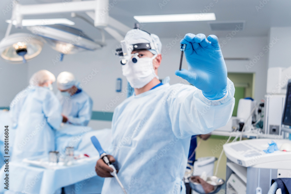 Spinal surgery. Surgeon show polyaxial screw in operating room with ...