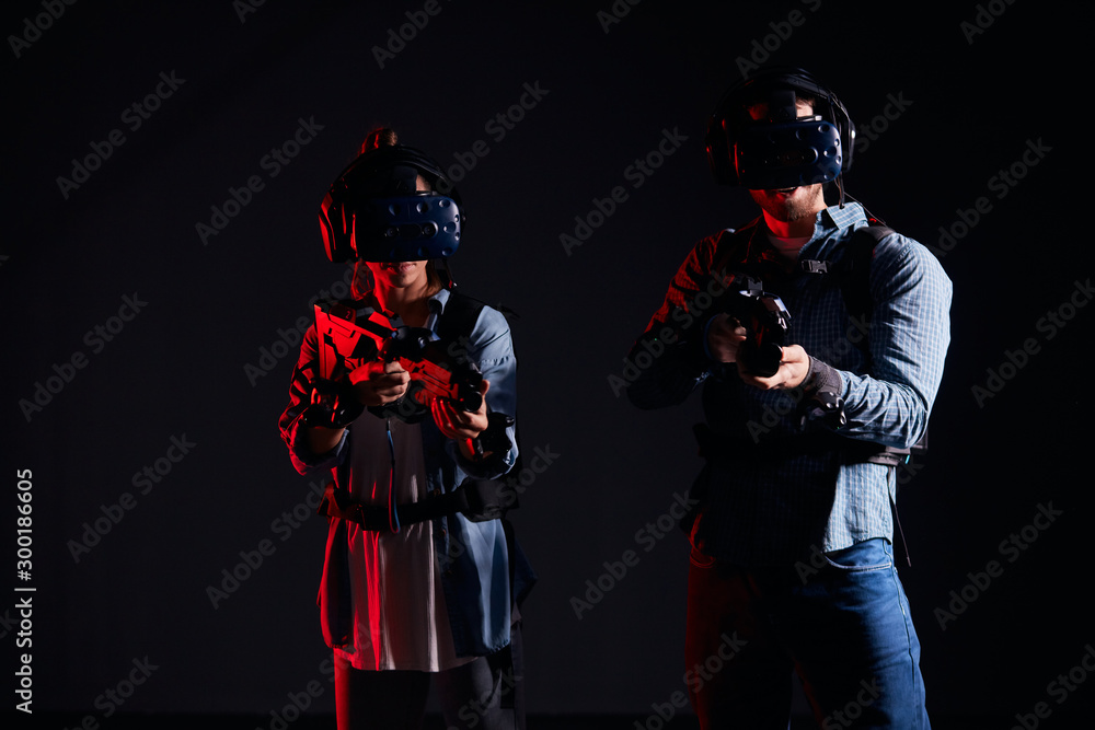 Youg couple direct their virtual weapons at camera, in search of enemy ...