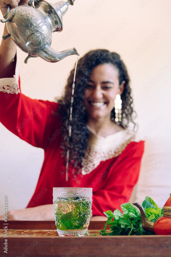 Young arabian woman pouring traditional arab tea at home. Morocco ...