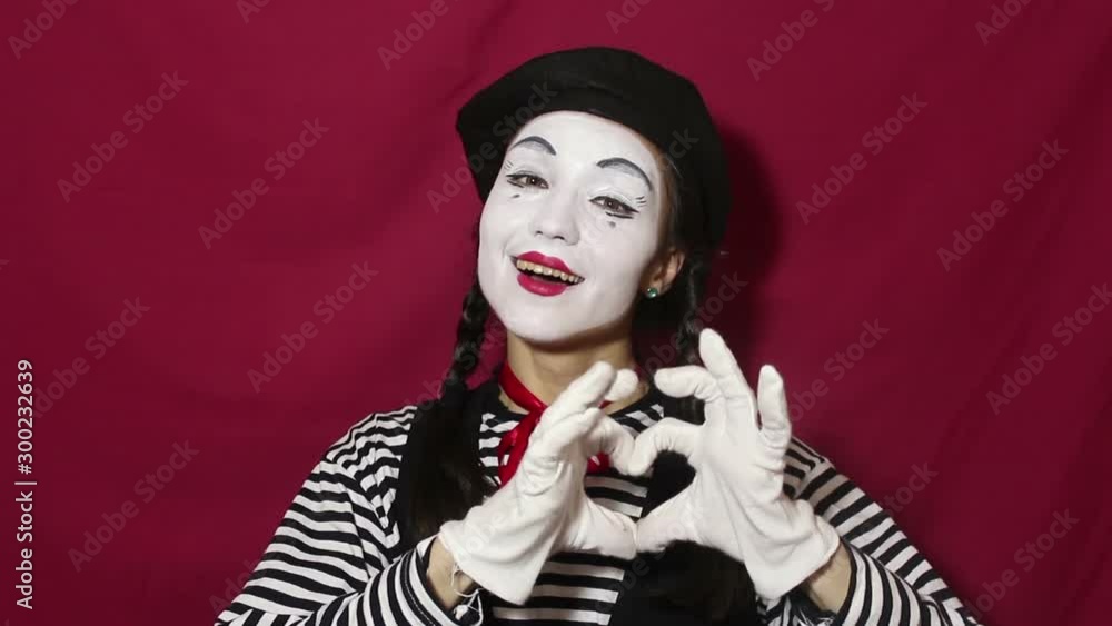 Beautiful girl mime smiles and makes a gesture of a beating heart with ...
