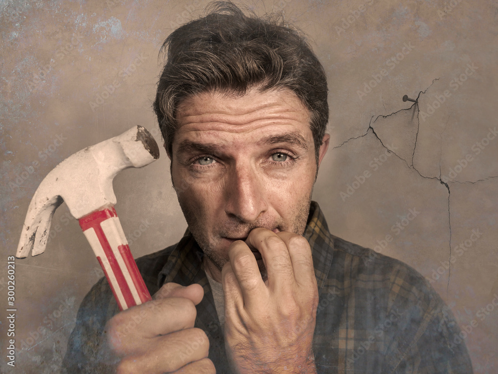man holding hammer driving a nail for hanging a frame but making funny ...